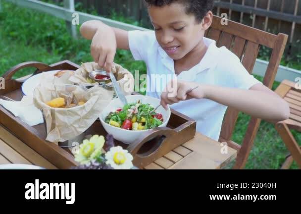 hungry african american teenager eating vegetable salad with fork in ...