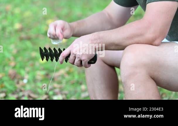 A man is cleaning the brush cutter attachment after cutting bushes ...