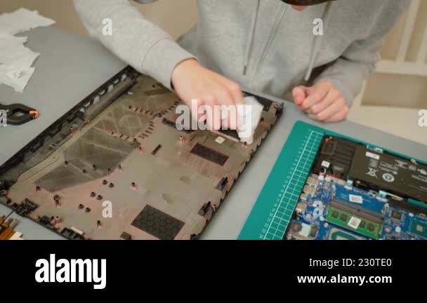 Boy cleaning laptop bottom cover with cloth during maintenance ...