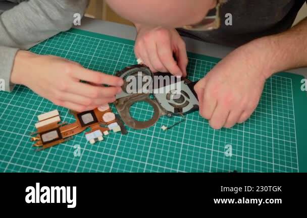 Father helping son clean laptop fans, carefully disassembling cooling ...