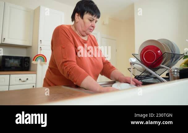 Woman washing dishes in sink. Female cleaning kitchenware in modern ...
