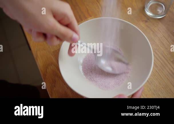 Teen boy pouring jelly powder into white bowl. Male teenager adding ...