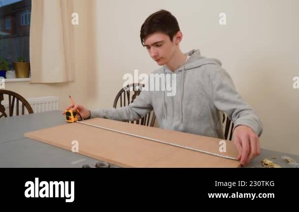 Boy holding pencil and tape measure, drawing straight guidelines. Male ...