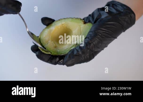 A detailed closeup of gloved hands skillfully slicing an avocado in ...