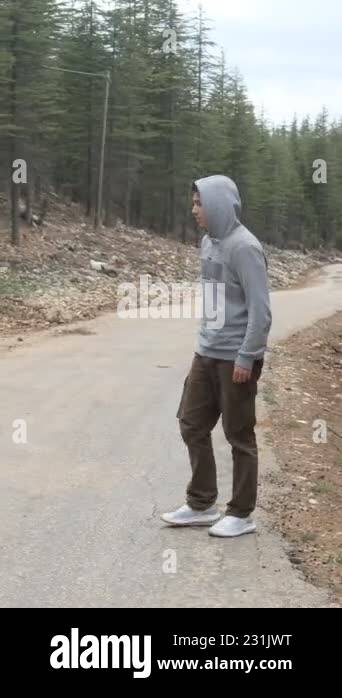 Young man hitchhiking on asphalt road in forest , intermediate stop ...
