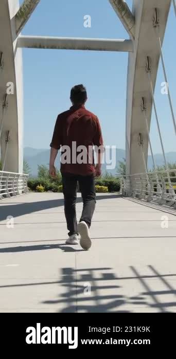 Young man crossing the bridge, back view of young man crossing the ...