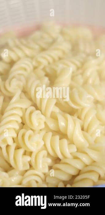 Straining boiled pasta, using kitchen utensils, preparing meal for ...