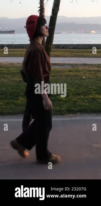 Image of young woman walking on beach by sea, woman in hat doing brisk ...