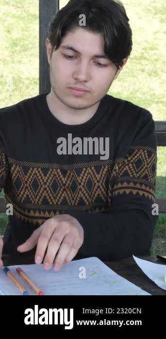 Image of lonely man studying in park, young man doing homework in ...