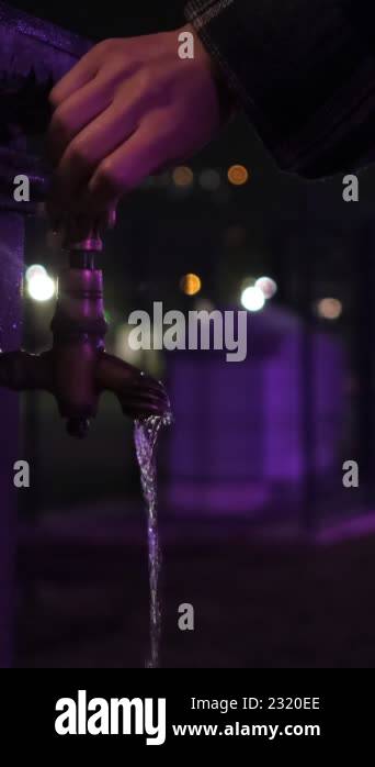 Close-up view of water flowing from public fountain, washing hand with ...