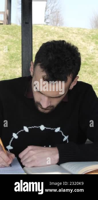 Image of lonely man studying in park, young man doing homework in ...