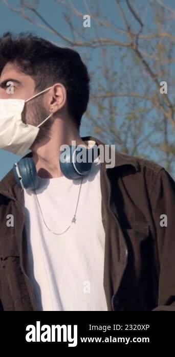 Young man with a health mask on his face stands in the park outdoors ...