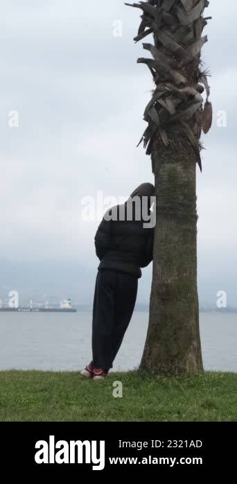 Thoughtful young man messing around by the sea in windy weather ...