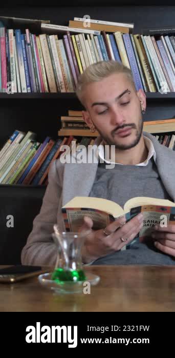 Concept of young man carefully reading a book with his back to the ...