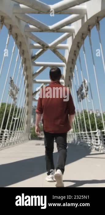 Young man crossing the bridge, back view of young man crossing the ...