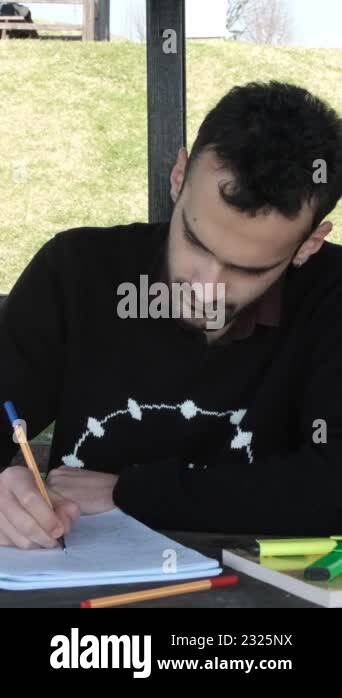 Image of lonely man studying in park, young man doing homework in ...