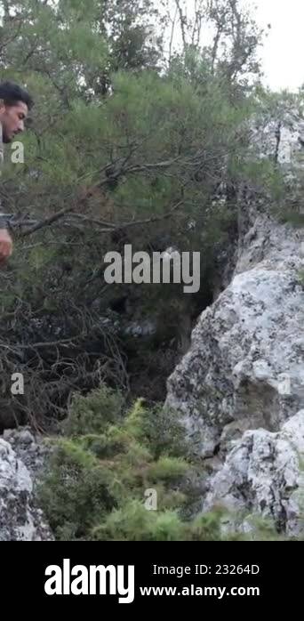Young caucasian bearded man jumping from stone to stone, sporty man in ...
