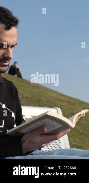 Image of lonely man reading novel on white bench in sunny day ...