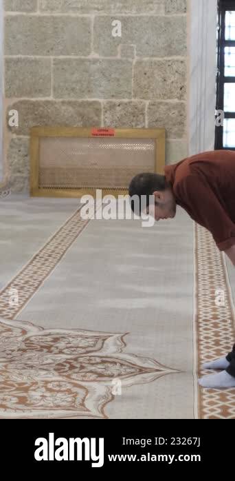Muslim man praying in a mosque, bowing on his knees, performing ruku ...