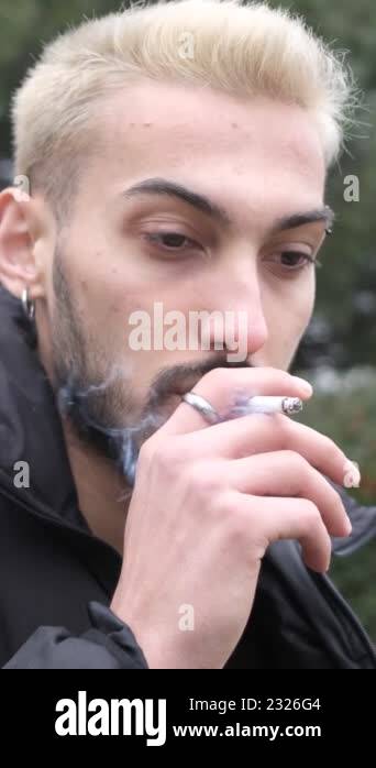 Image of young man smoking in park, young man contemplating looking ...