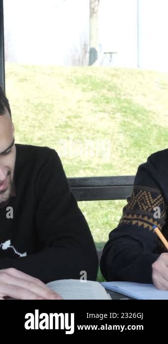 Image of studying in park with close friends , young man doing homework ...