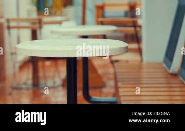 Outdoor cafe seating with round tables and wooden benches on a tiled ...