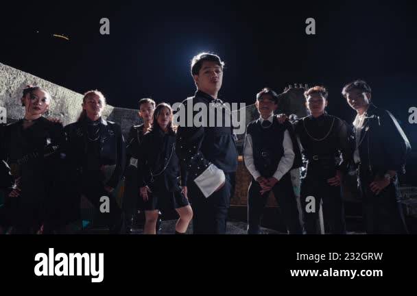 A group of eight stylish individuals posing confidently in a dramatic ...