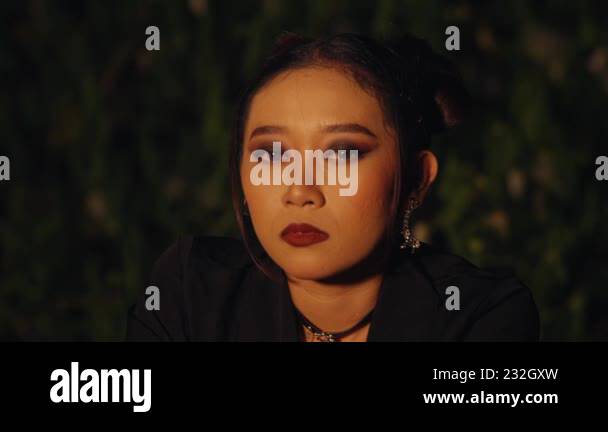 A young woman with dramatic makeup, including dark eyeshadow and bold ...