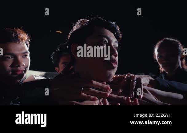 A dramatic scene featuring a group of young people in a dimly lit ...