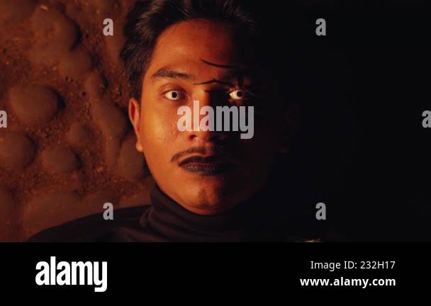 A dramatic portrait of a man with striking makeup, featuring a half-lit ...