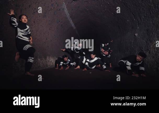 A dramatic scene featuring a young man in a black outfit standing ...