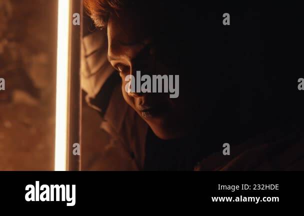 A close-up portrait of a young person with a contemplative expression, illuminated by a soft ...