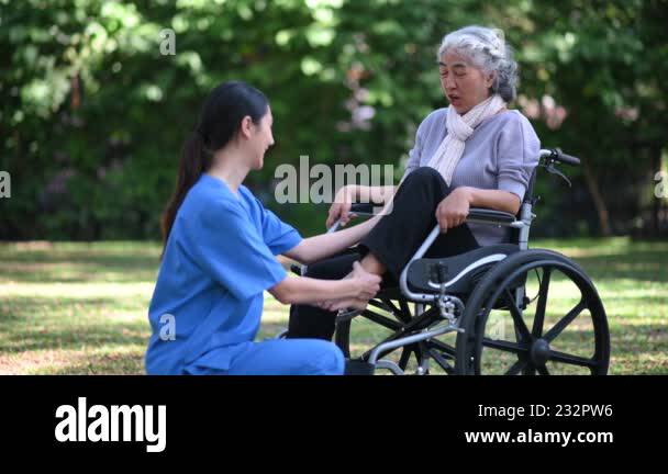 Young nurse taking care of asian senior woman on wheelchair, making ...