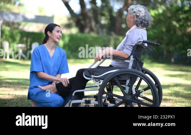 Young nurse taking care of asian senior woman on wheelchair, making ...