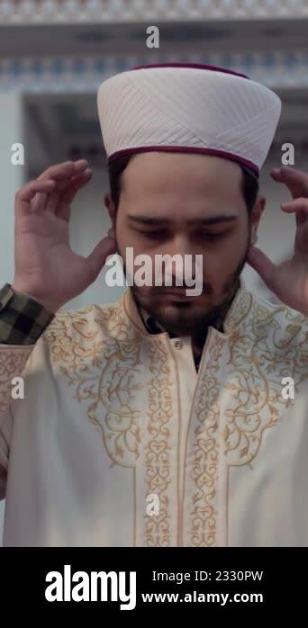 Mosque teacher standing in the masjid takes his hands to his head to ...