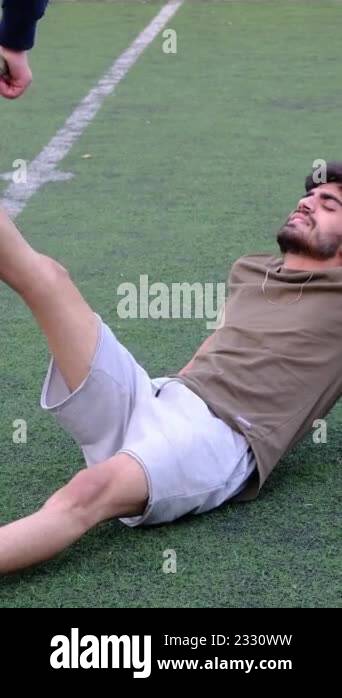 Standing man doing movement of young mans legs lying on the carpet ...