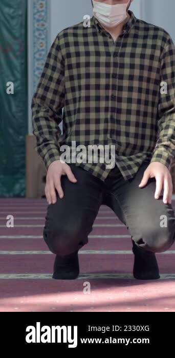 Front view shot of young man with mask on his face praying in mosque ...
