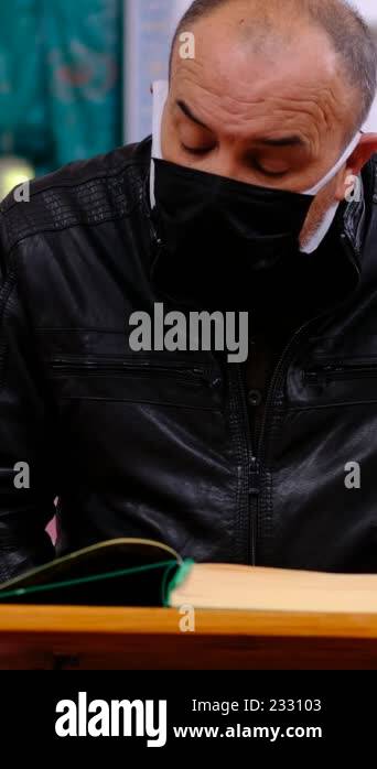 Front view of an old man with a black mask on his face reading the ...