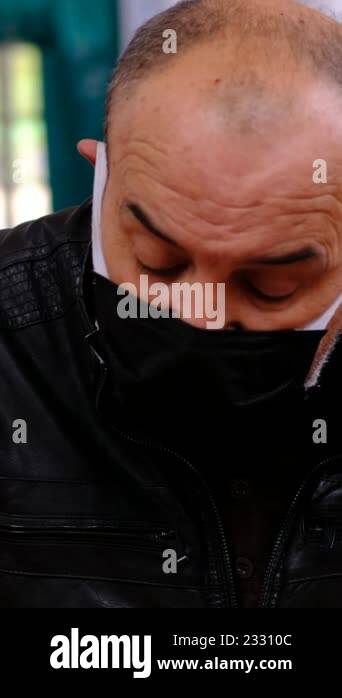 Front view of an old man with a black mask on his face reading the ...