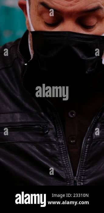 Close-up of an adult man with a black mask on his face praying in a ...
