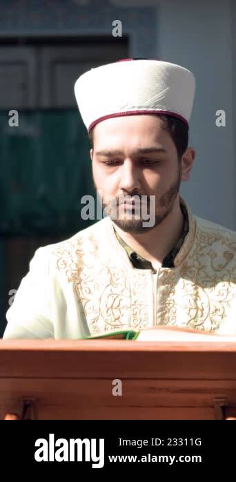 Front view shot of imam sitting alone in mosque reading quran standing ...