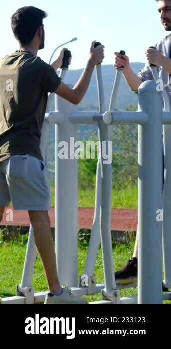 Back shots of two young friends talking while exercising on the gym ...