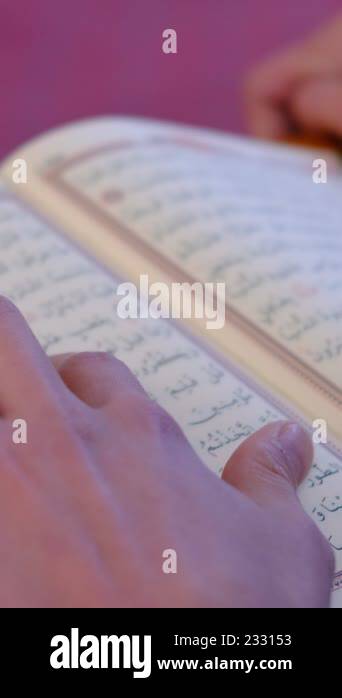 Close up view of finger following lines of quran standing on table ...