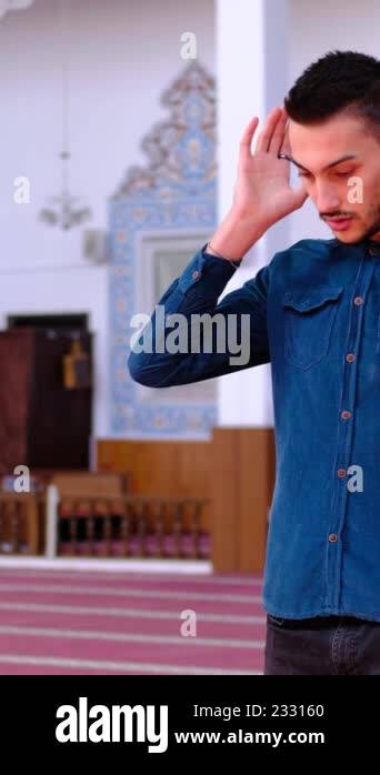 Young man in blue shirt takes his hand to his head to start prayer in ...