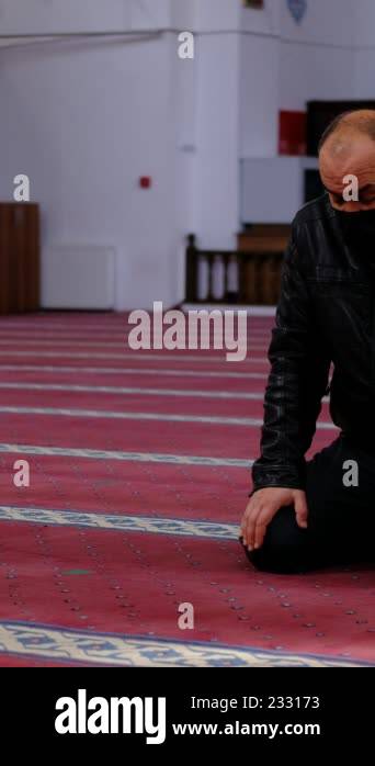 A man with a black health mask on his face praying in the mosque, a ...