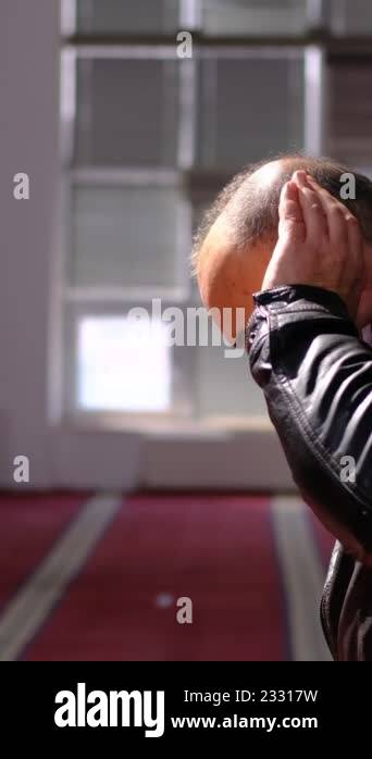 Side view of mature man with face mask starting prayer in masjid, men ...