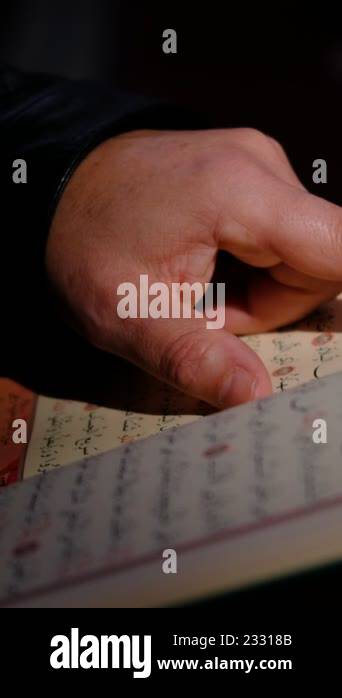 Reading the Quran he is holding with his finger, the holy book of Islam ...