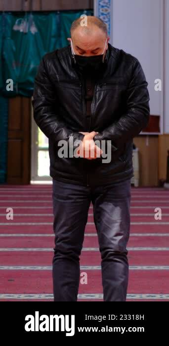 Mature man with black mask on his face is standing in mosque starting ...