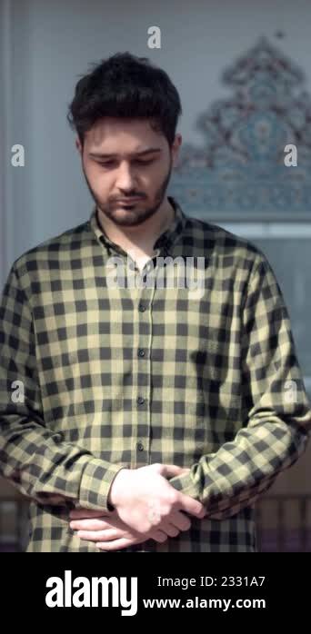 Man with his hand on his belly in the mosque bows while praying, front ...