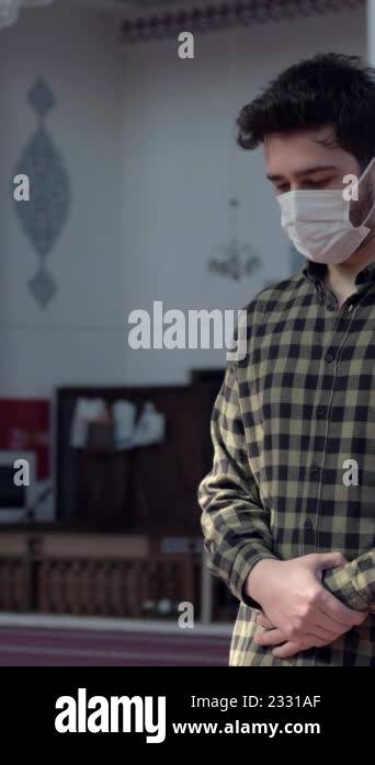 Different angle view of young man with mask on face praying in mosque ...